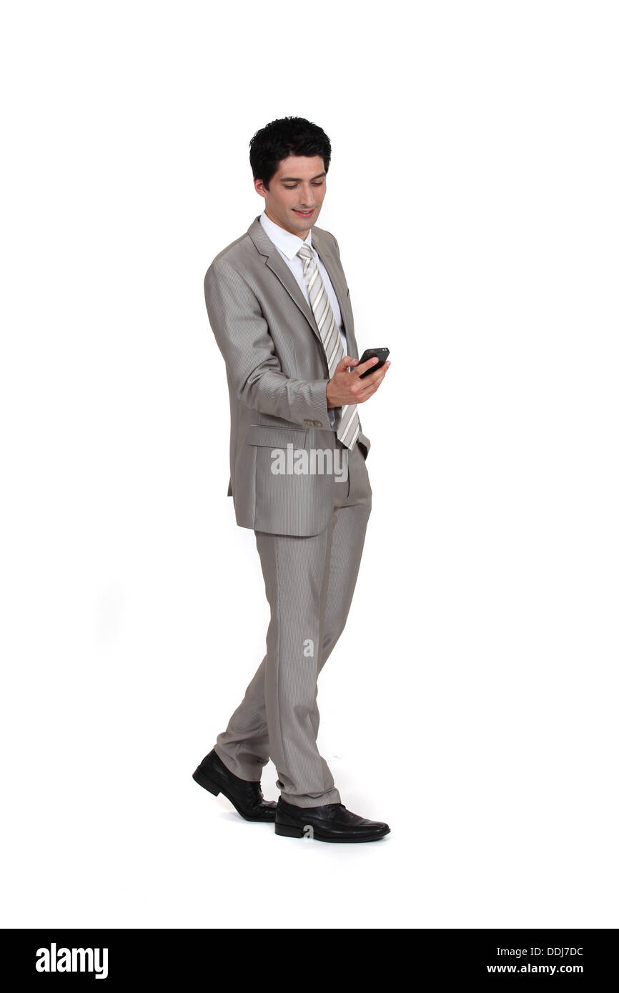 Young businessman sending text message whilst walking Stock Photo - Alamy
