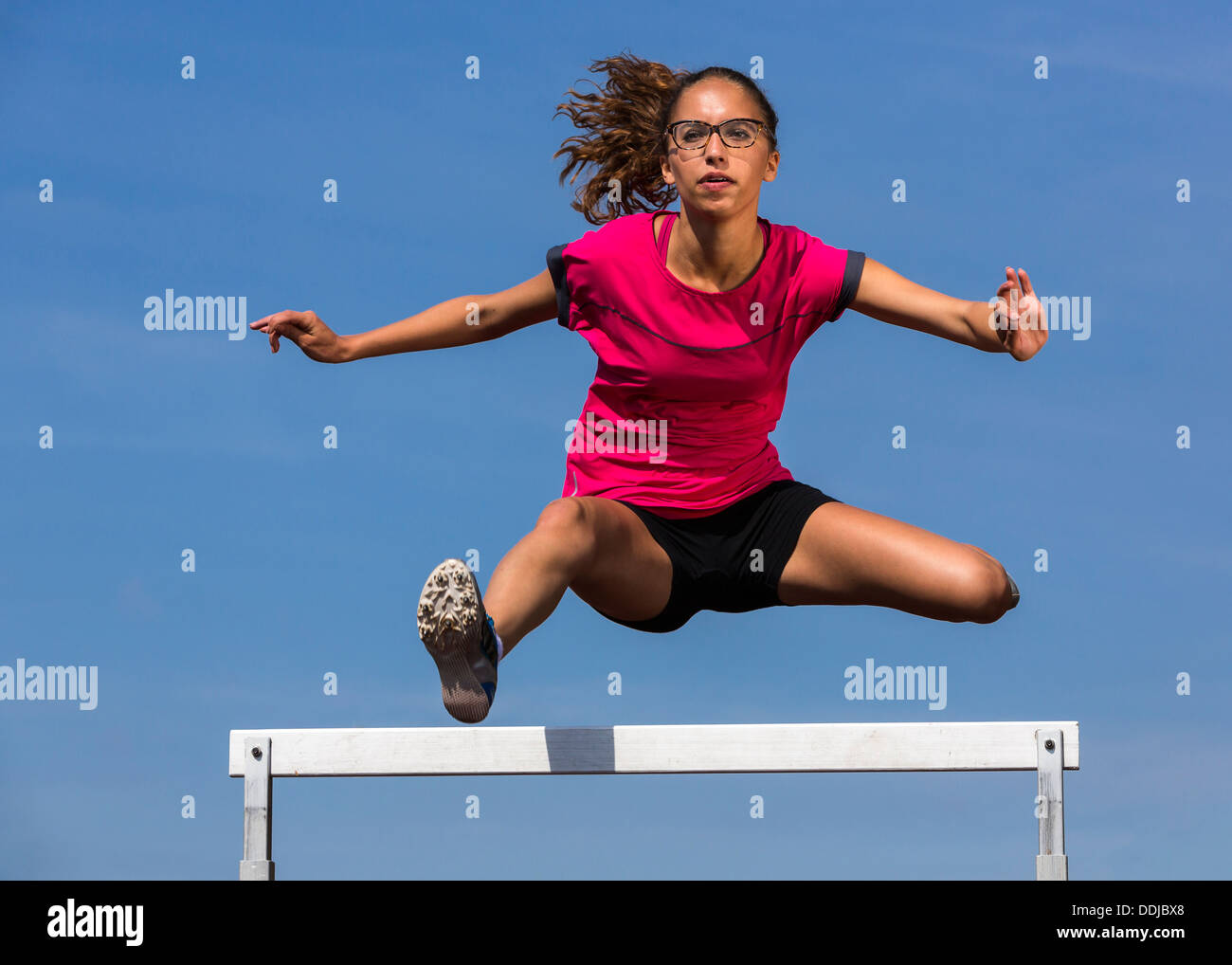 Germany, Young woman athlete jumping hurdles on track Stock Photo - Alamy
