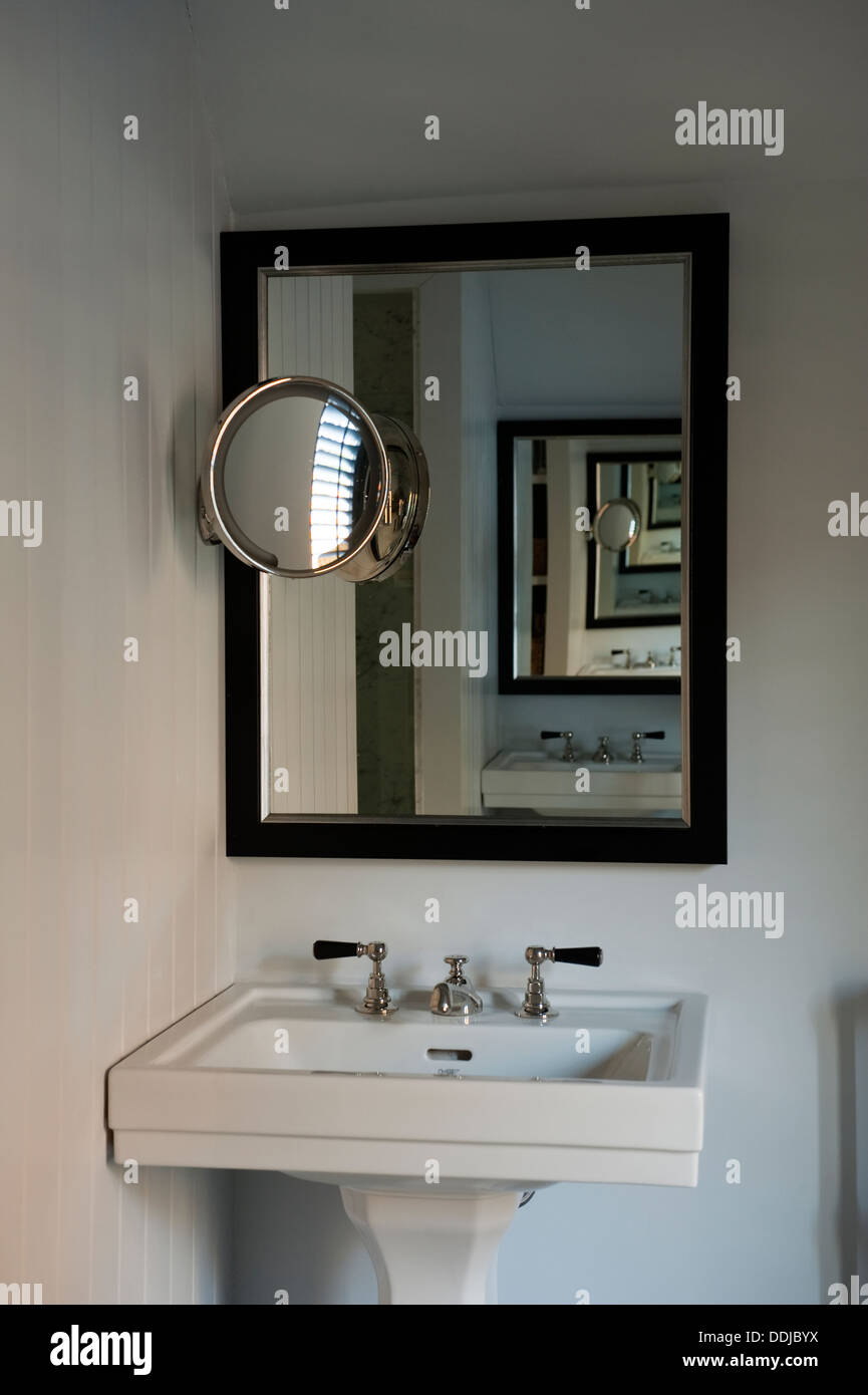 Hand basin with nickle taps and nickle circular mirror Stock Photo - Alamy