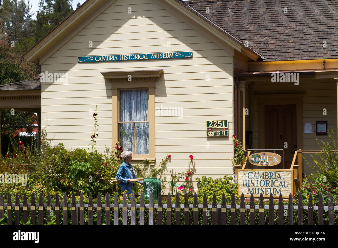 Elderly woman with flags walking in front of Cambria Historical Museum ...