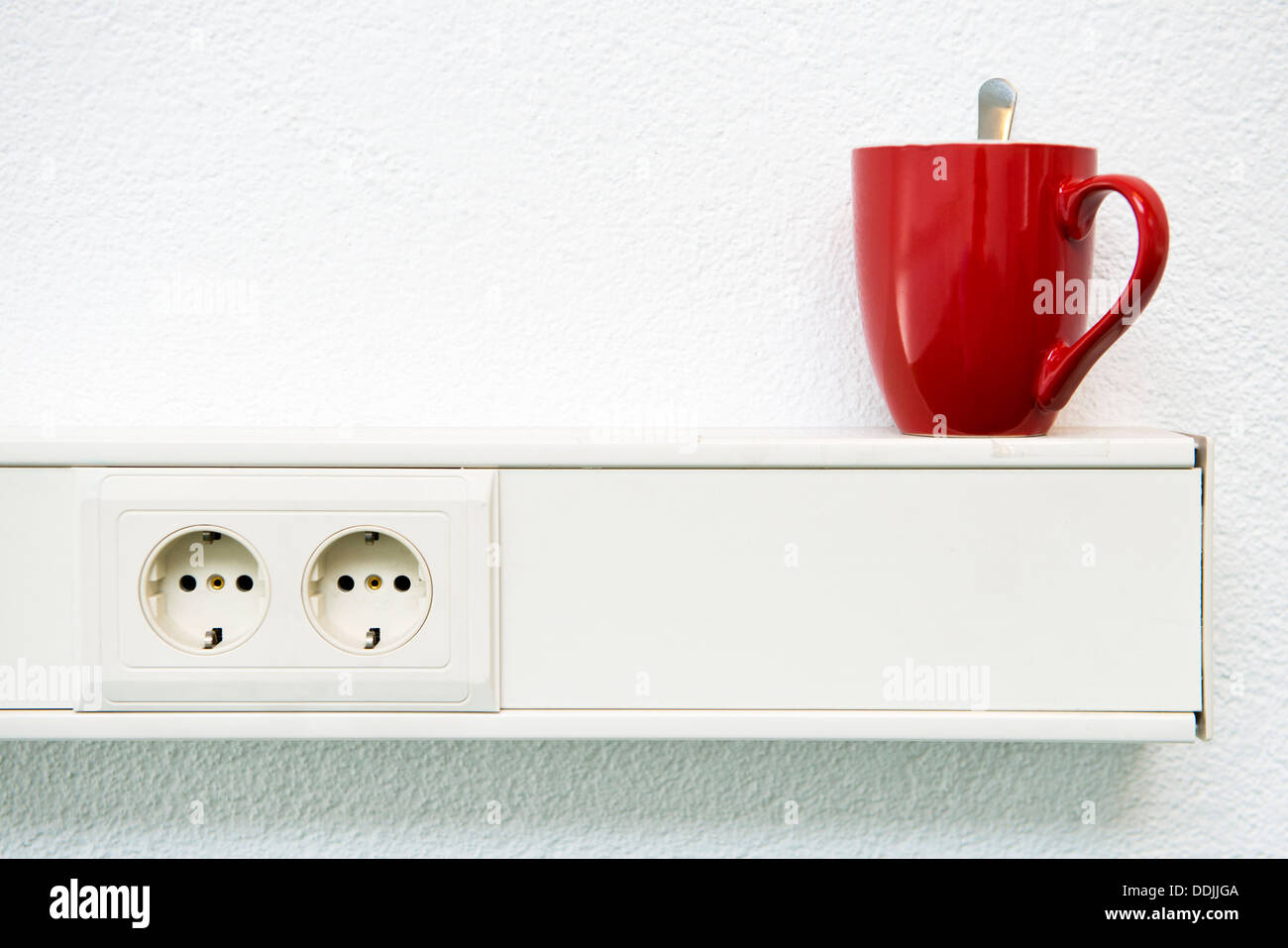 Red mug with a spoon standing on an electrical bar with two power ...