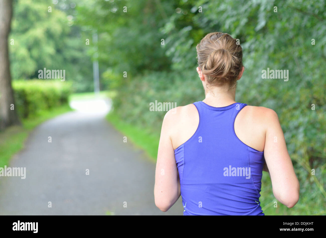 Young athletic woman running down a path Stock Photo - Alamy
