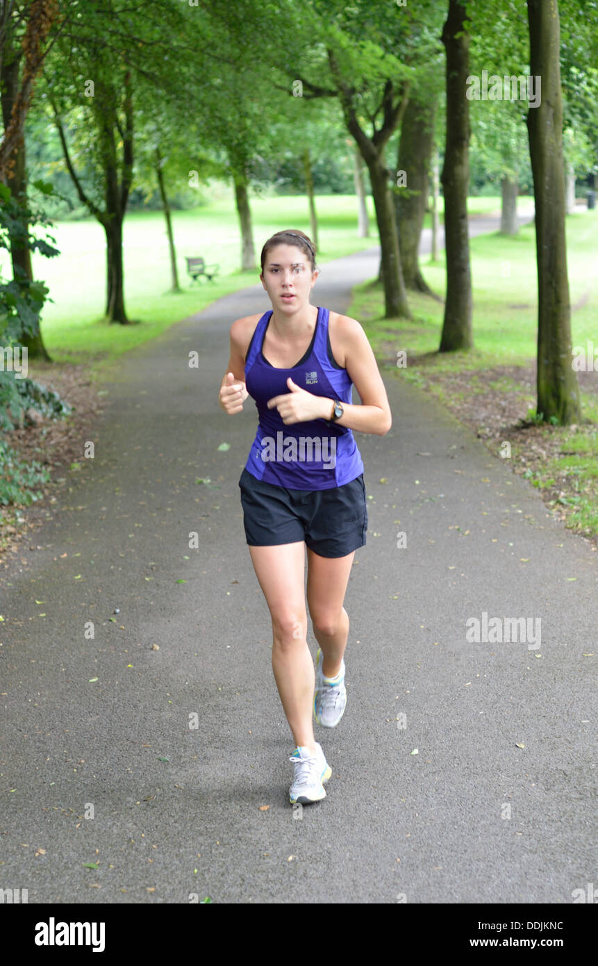 Young athletic woman running down a path towards camera Stock Photo - Alamy
