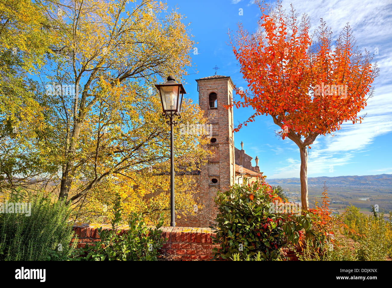 Old brick bell tower as seen among trees with red and yellow leaves in ...