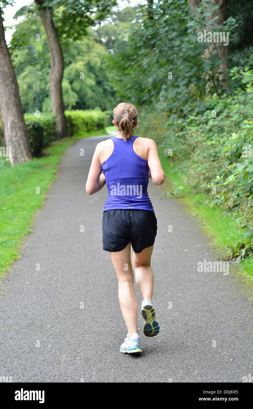 Young athletic woman running down a path Stock Photo - Alamy