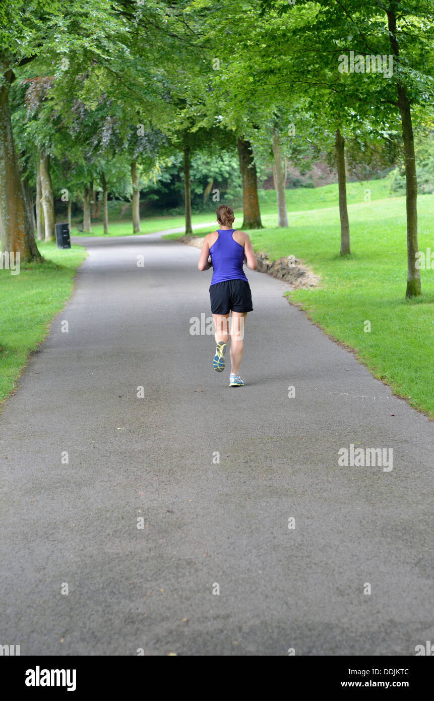 Young athletic woman running down a path Stock Photo - Alamy