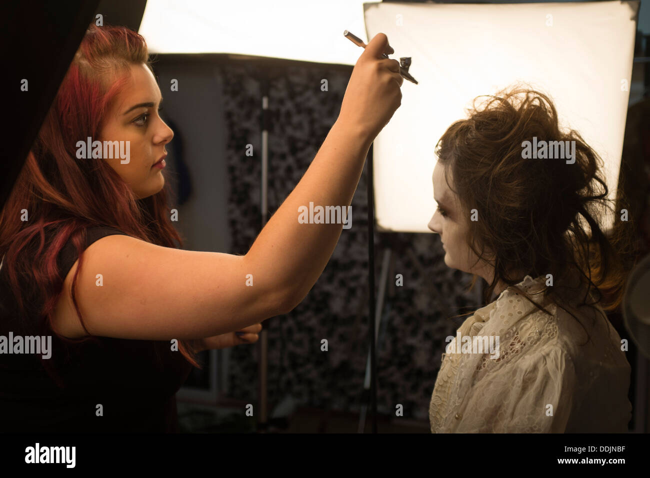 A make up artist getting a female model ready for a photo shoot in a ...