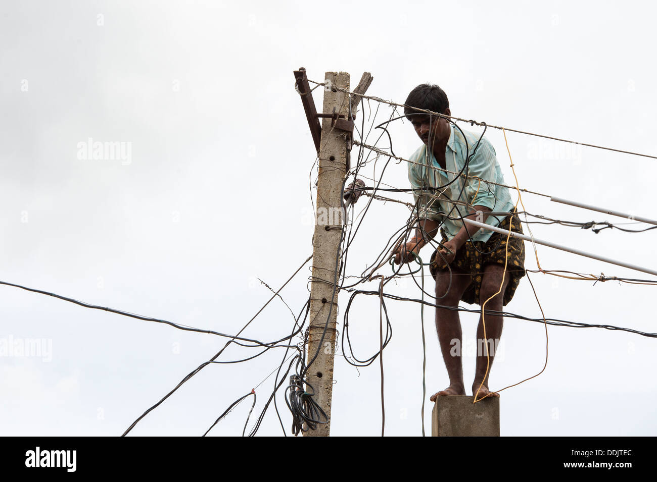 Indian man, Electriction working up an Electricity pylon replacing ...