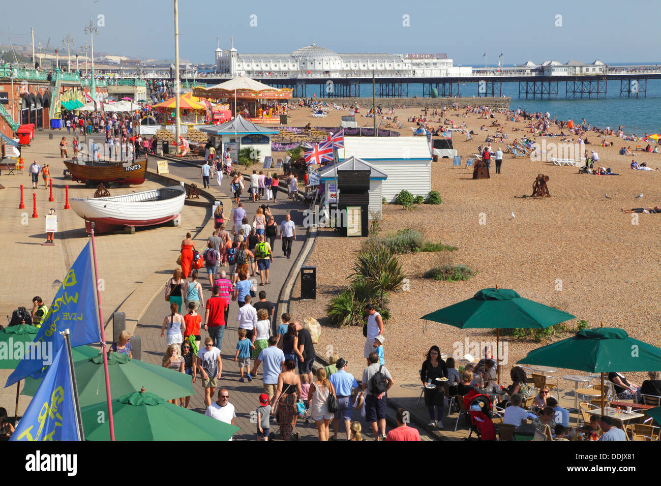 People walking on Brighton promenade and sunbathing on the beach East ...