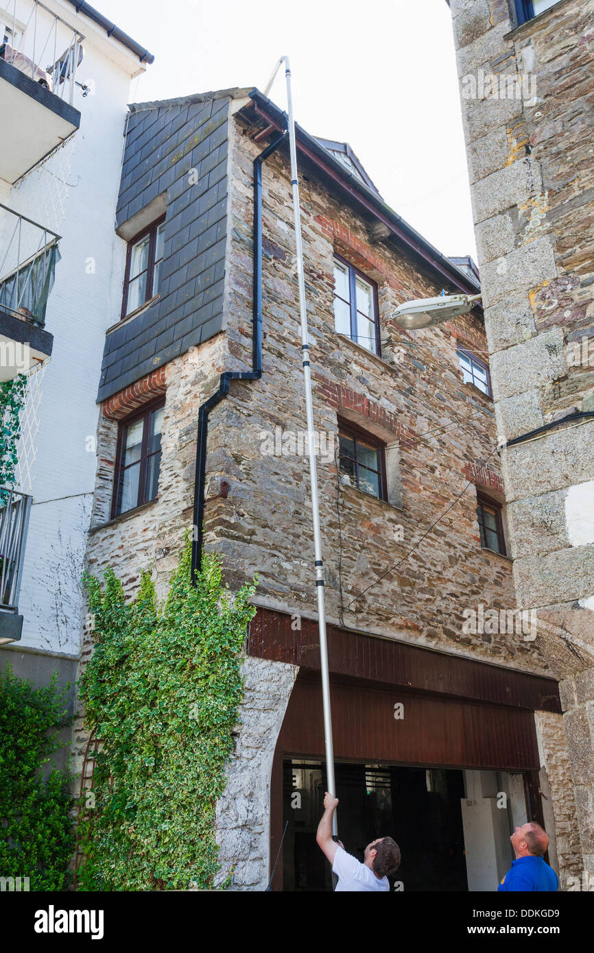 England, Cornwall, Looe, Man Using Industrial Hoover to Clean Gutter ...