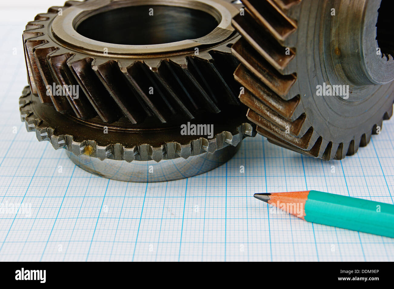 Gear and pencil on graph paper Stock Photo - Alamy