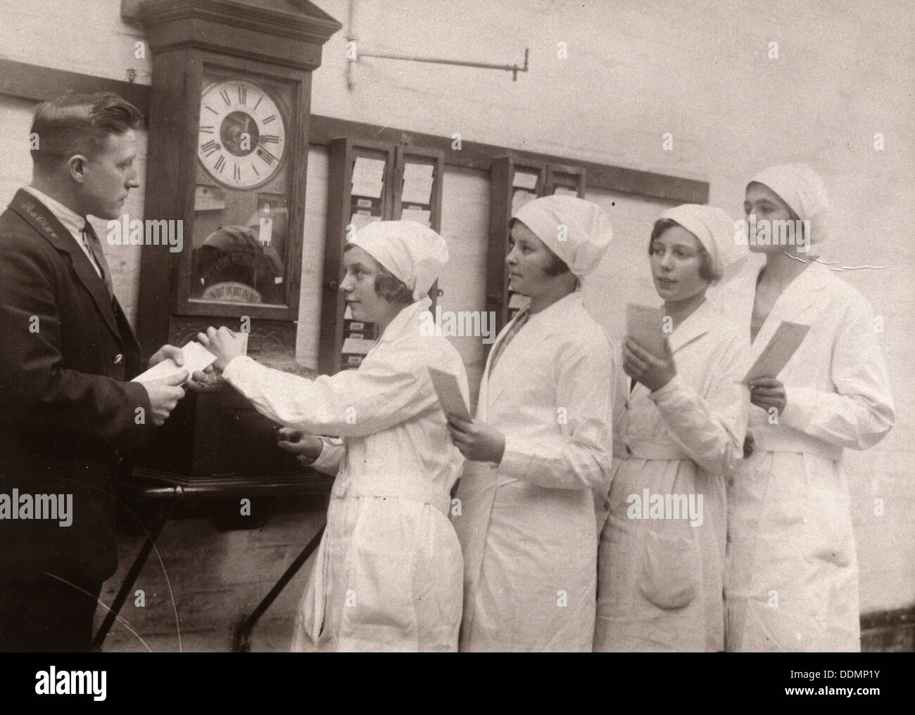 Girls queue at the Clocking-In machine, Rowntree factory, York ...