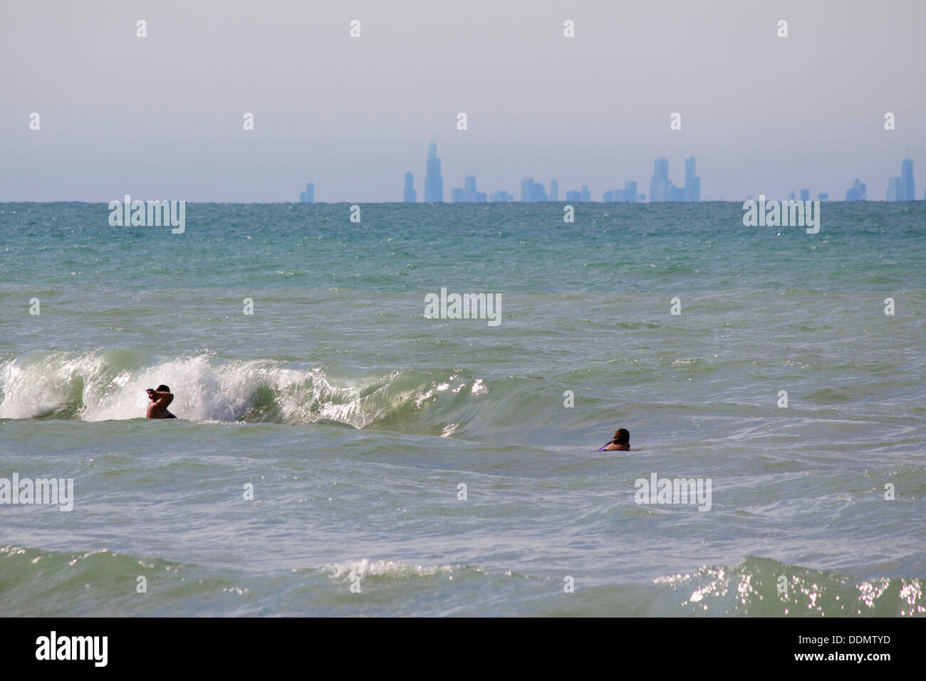 Bathers wade in the surf at Indiana Dunes State Park with downtown ...