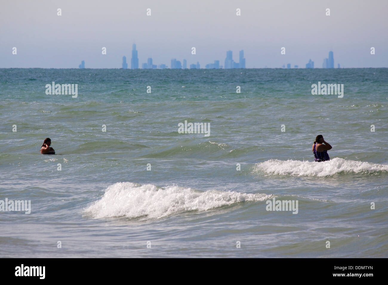 Bathers wade in the surf at Indiana Dunes State Park with downtown ...