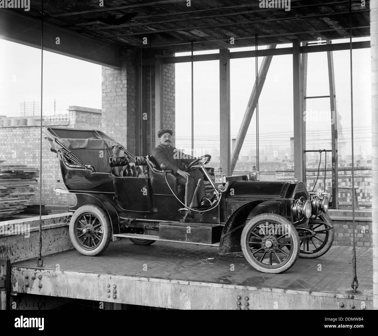 A car and chauffeur in the car lift at Mitchell's Motors, Wardour ...