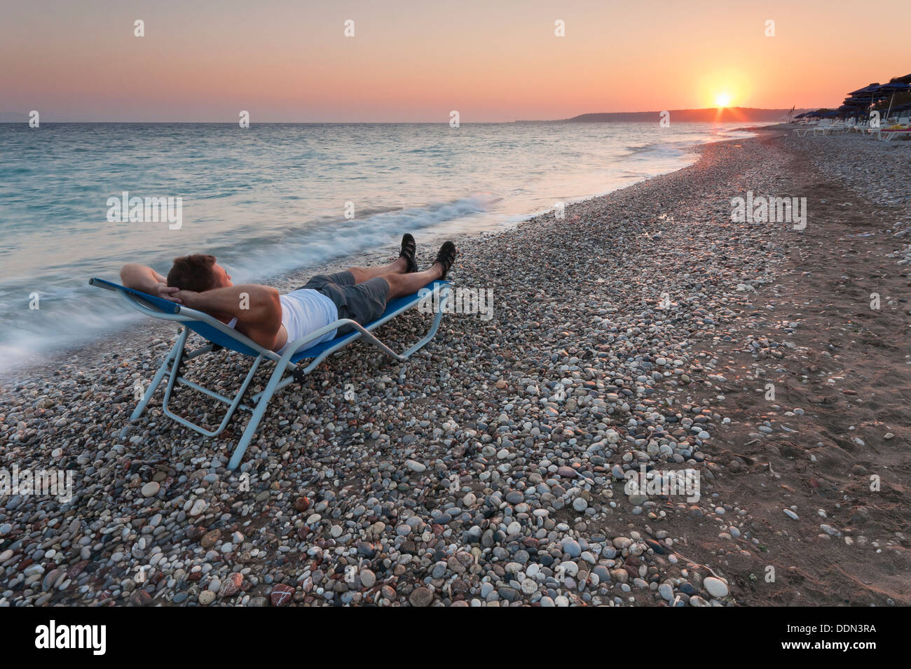 Man relaxing on the beach during sunrise Stock Photo - Alamy