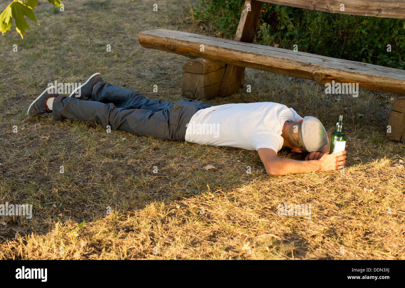 Jobless man sleeping on the ground outdoors next to a bench after ...
