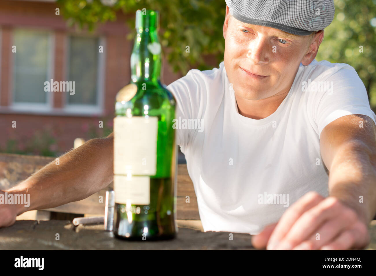 Horizontal portrait of a melancholic drunk man looking at a bottle of ...
