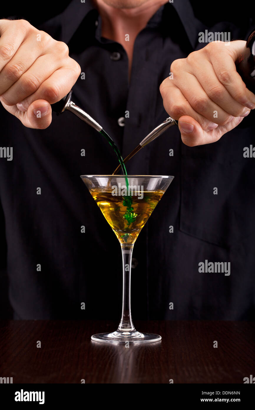 Bartender pours alcoholic drink into cocktail glass Stock Photo - Alamy