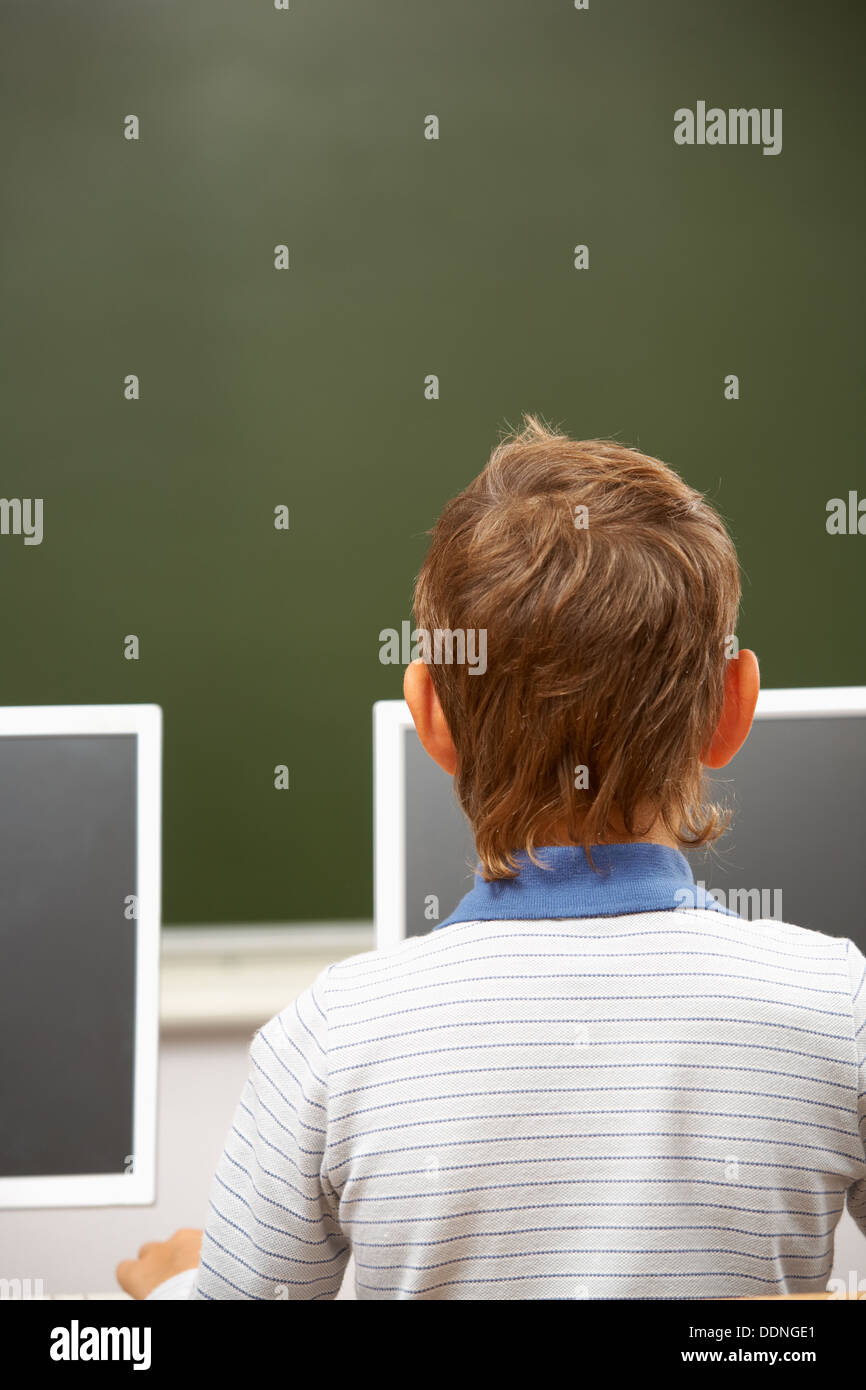 Rear view of cute lad in front of monitor in classroom Stock Photo - Alamy