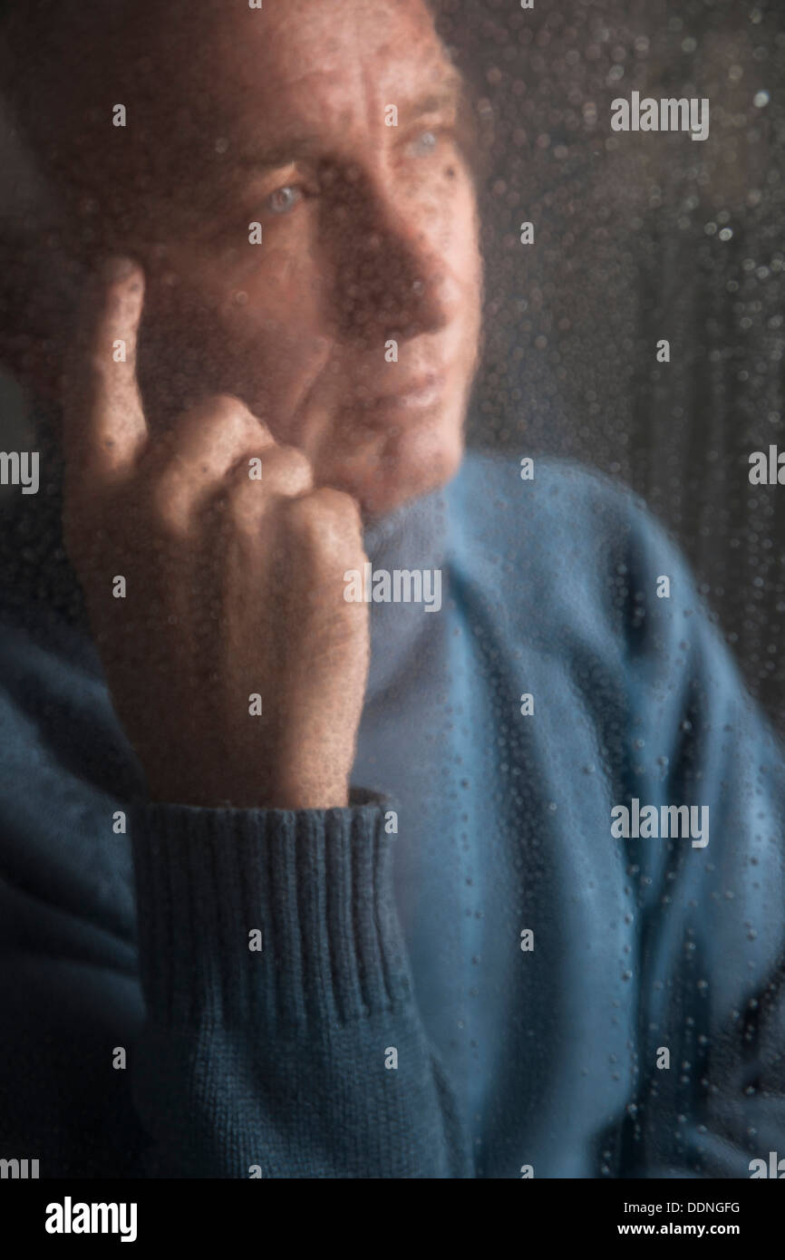 Serious mature man behind rainy window pane Stock Photo - Alamy