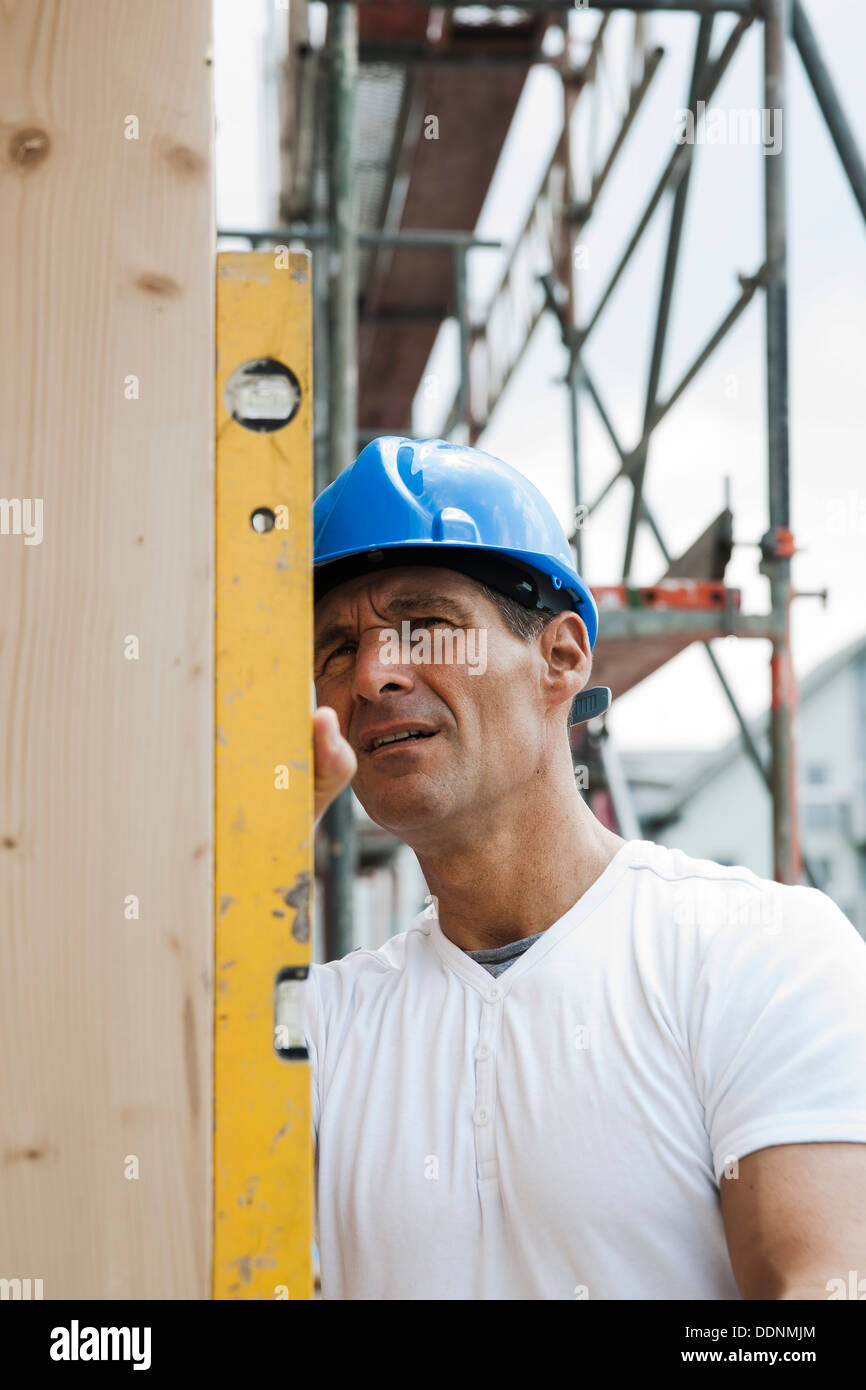 Builder with level on construction site Stock Photo - Alamy