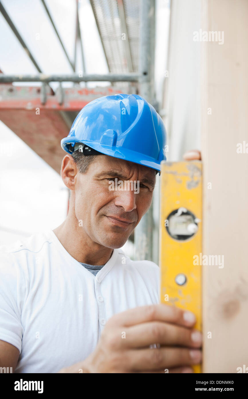 Builder with level on construction site Stock Photo - Alamy