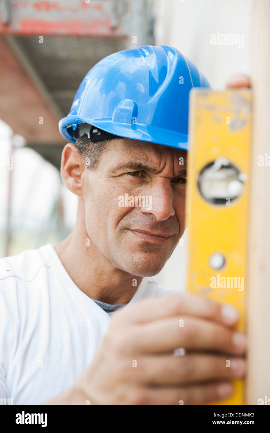 Builder with level on construction site Stock Photo - Alamy
