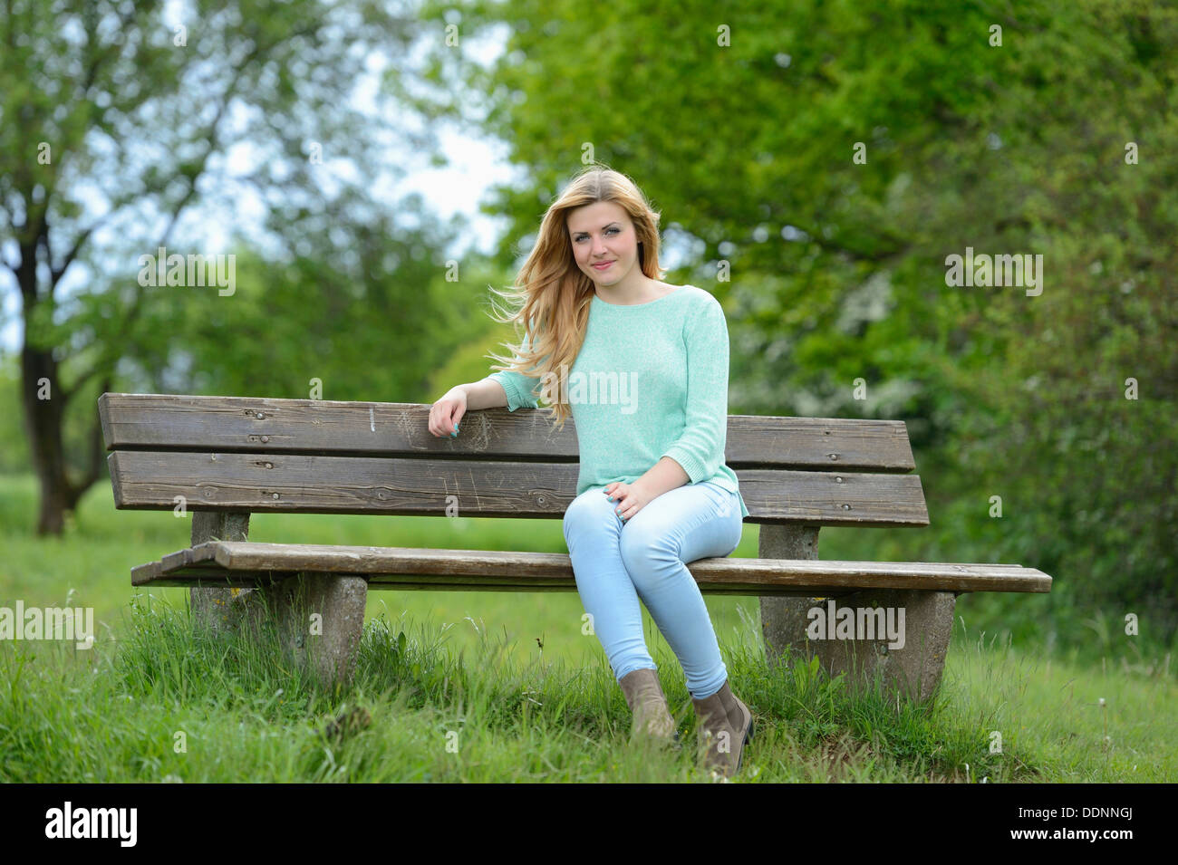 Blond young woman sitting on bench Stock Photo - Alamy