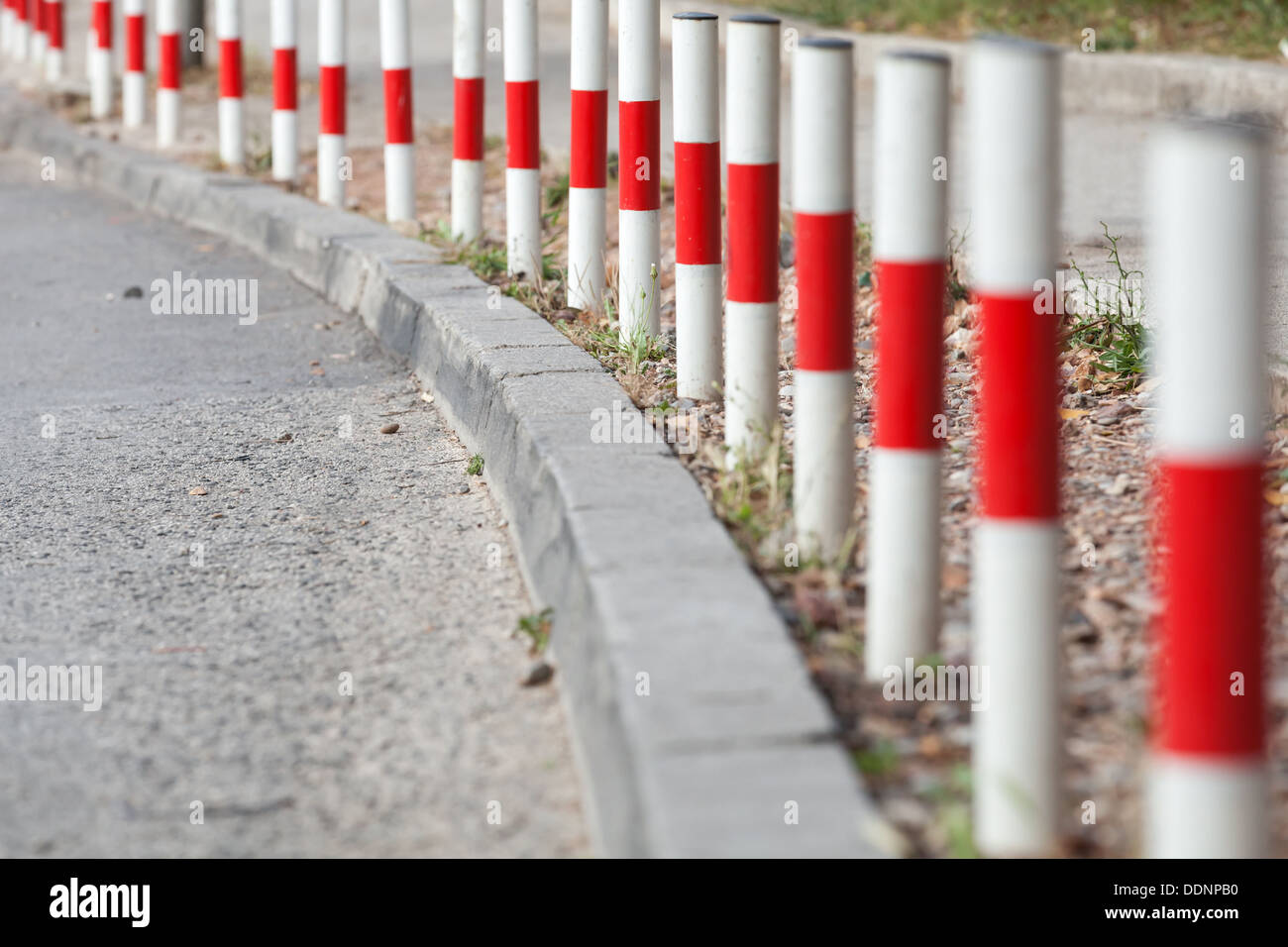 Striped red and white signal poles stand on border of asphalt roadside ...