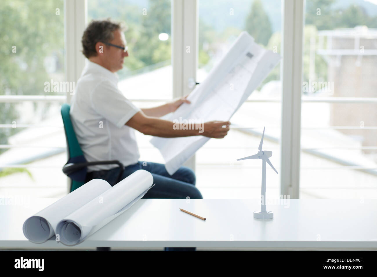 Engineer with blueprints in office Stock Photo - Alamy