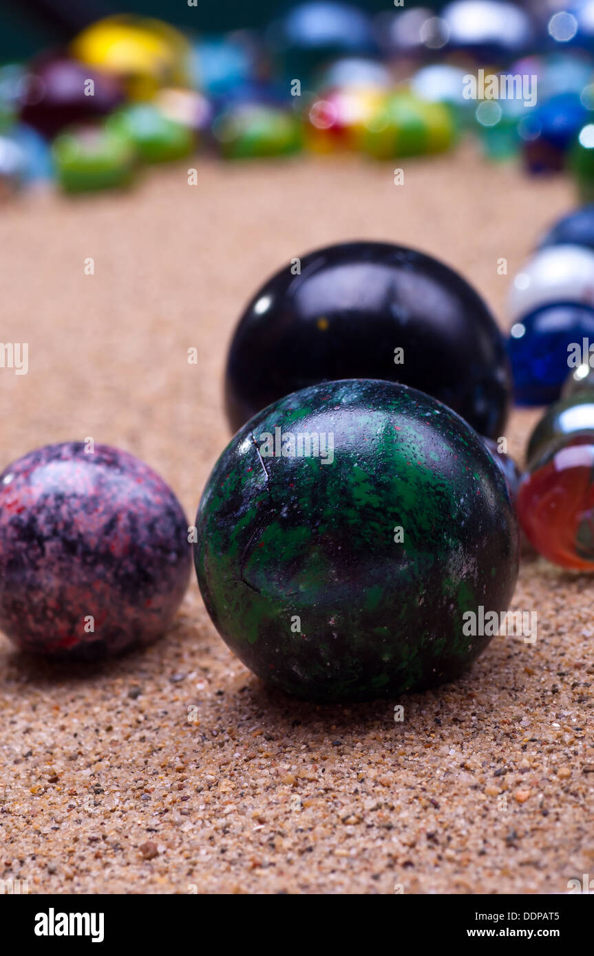 Colored glass marbles on a sandy background Stock Photo - Alamy