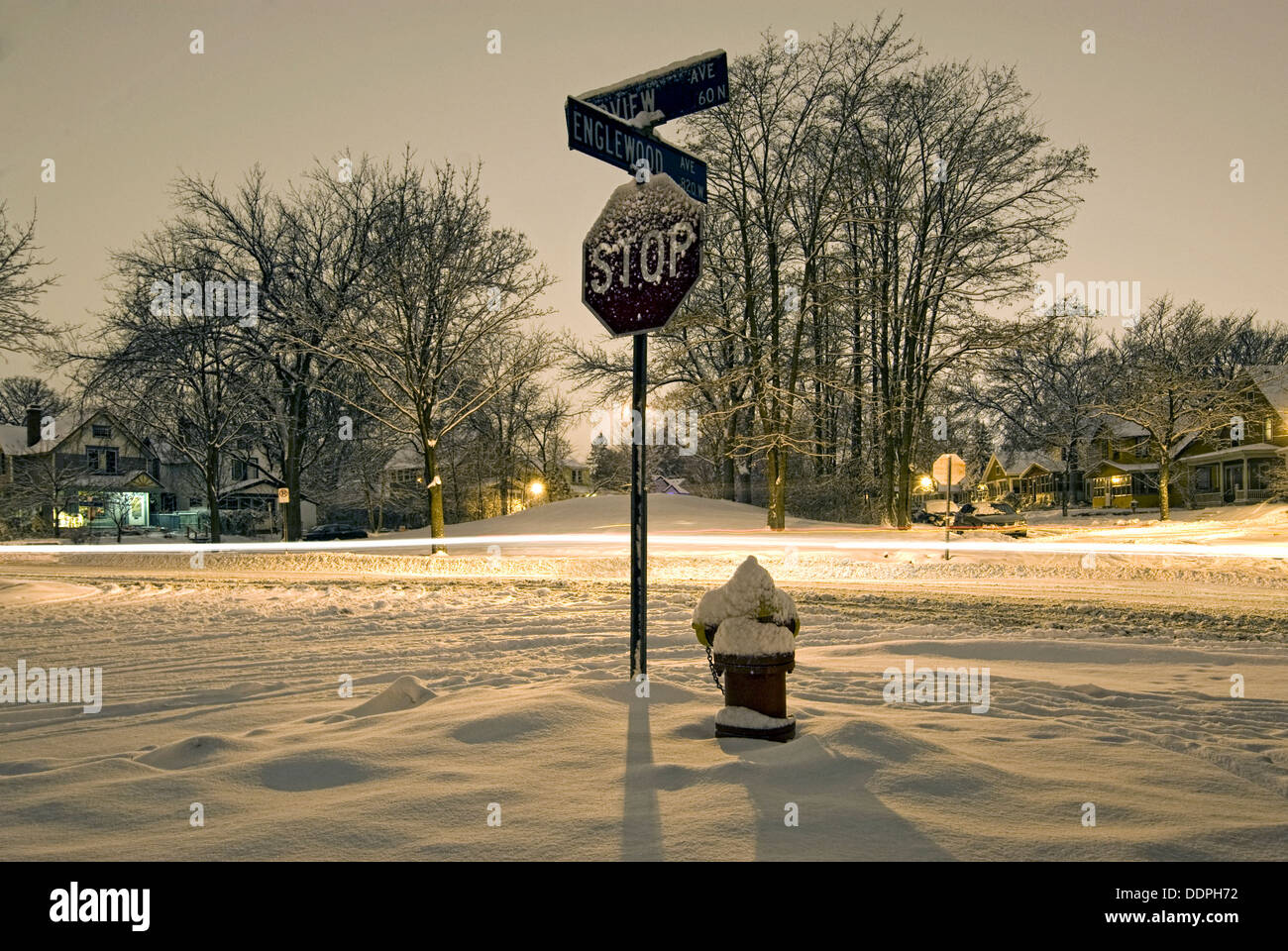 Stop sign, fire hydrant and street covered in snow, early morning. St ...