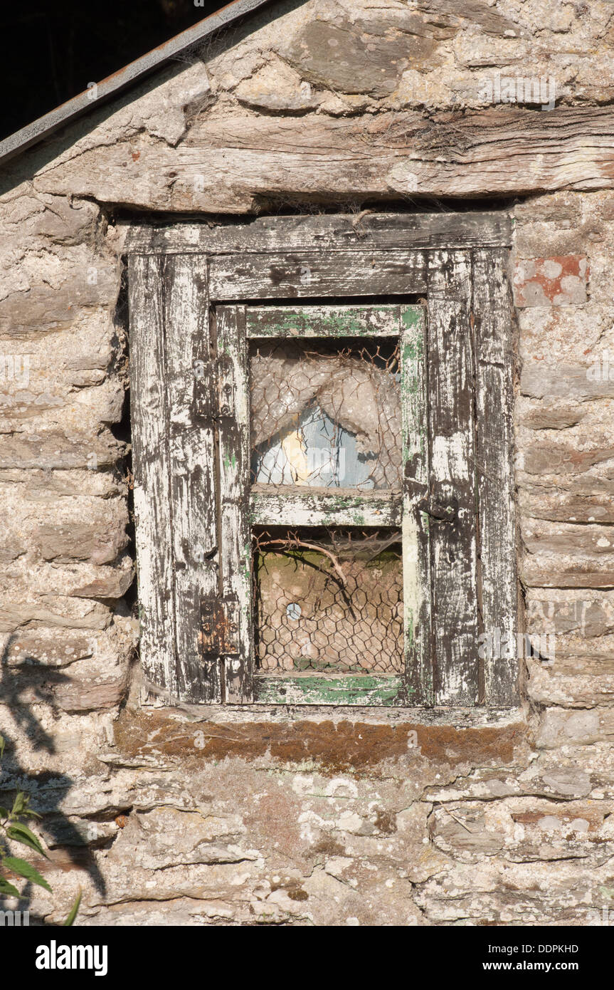 Weathered and broken window and frame with chicken mesh in stone ...