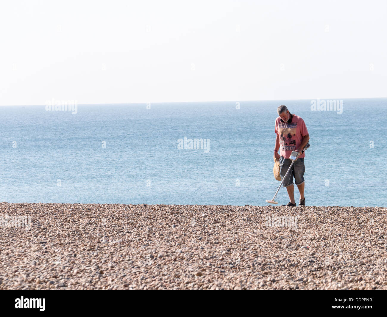 A man searches for treasure on the beach with a metal detector Stock ...
