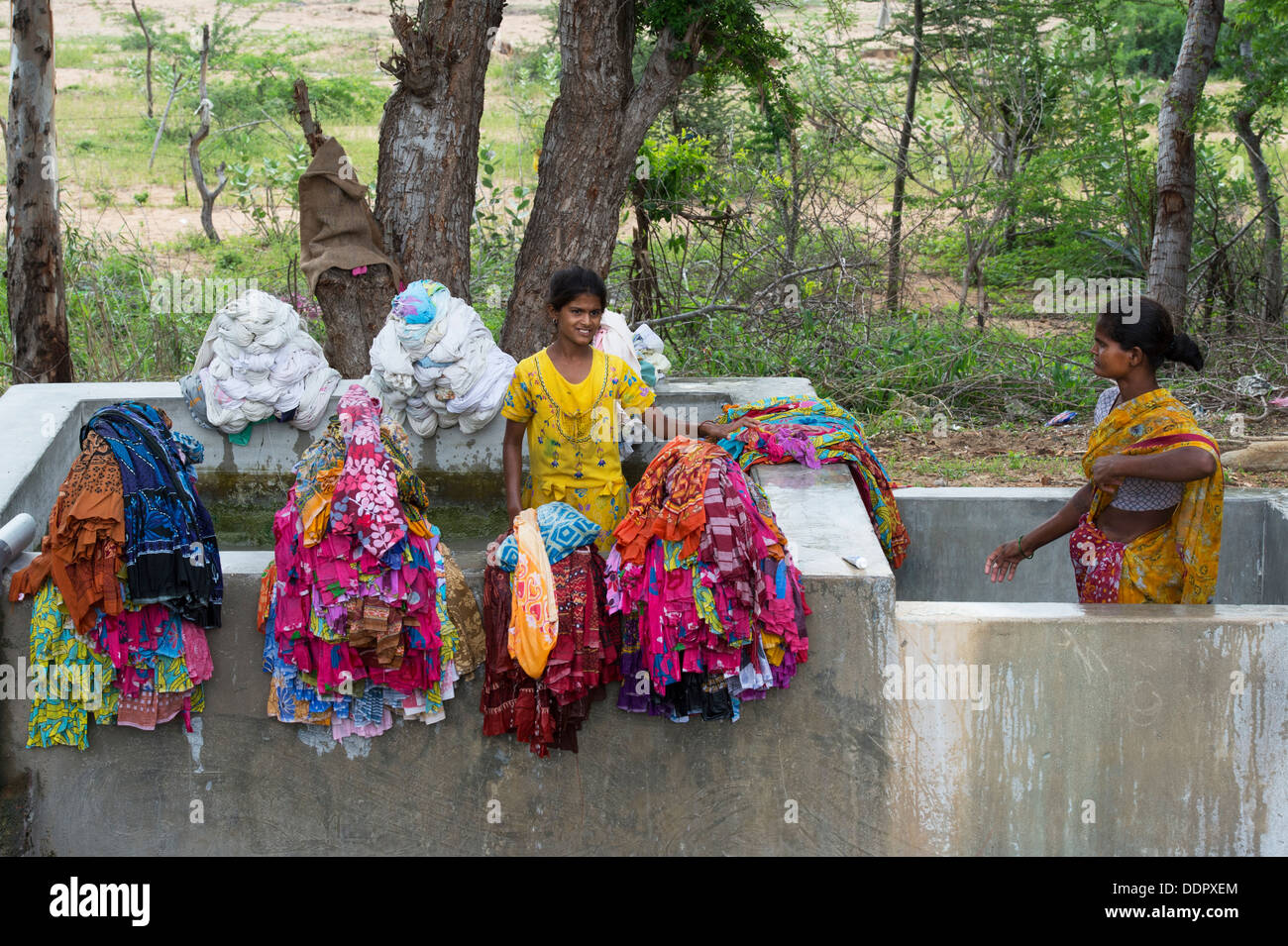 Indian mother and daughter washing clothes by hand in a large concrete basin. Andhra Pradesh ...
