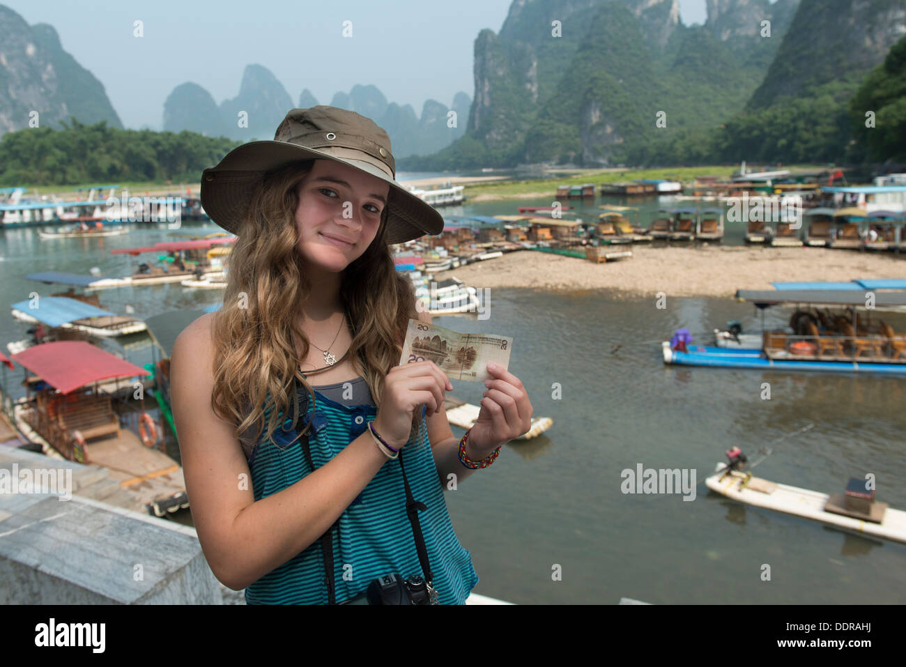 Teenage girl holding a Chinese yuan note at riverside, Li River ...