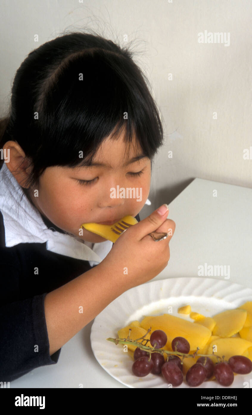 little chinese girl eating fruit Stock Photo - Alamy