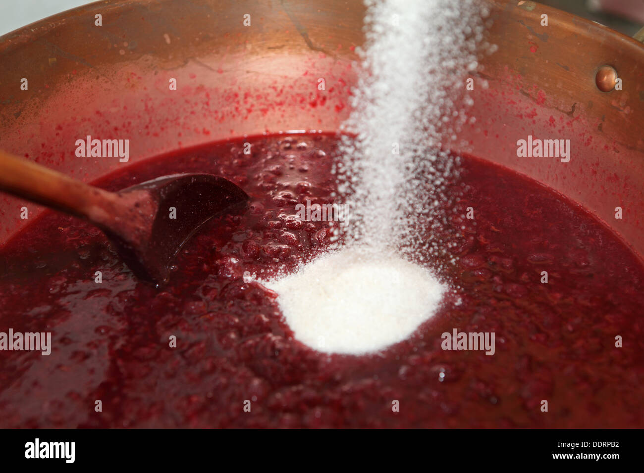 Preserving sugar being poured into a pan with fruit for jam making ...