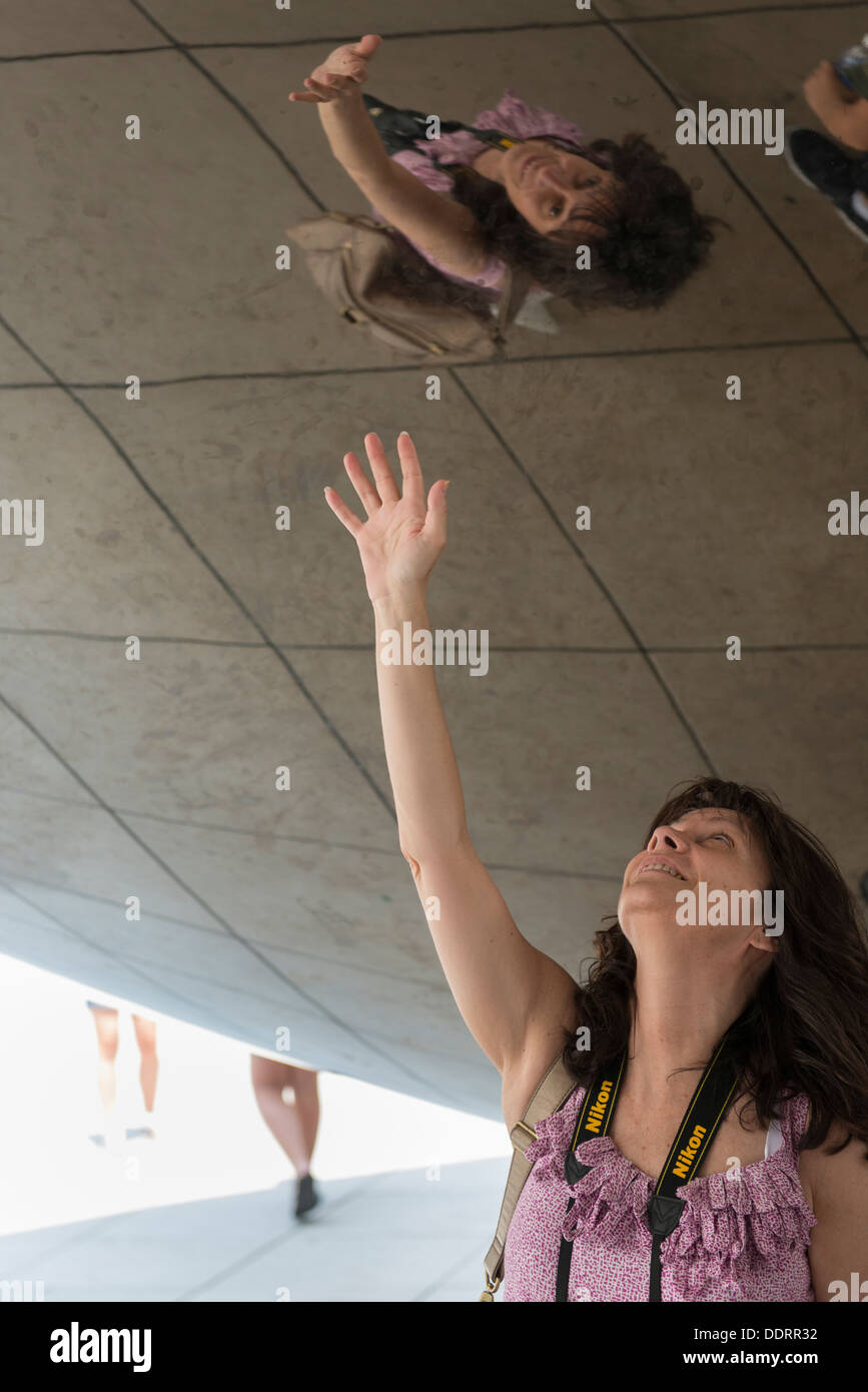 Woman touching her reflection on Cloud Gate, Millennium Park, Chicago ...