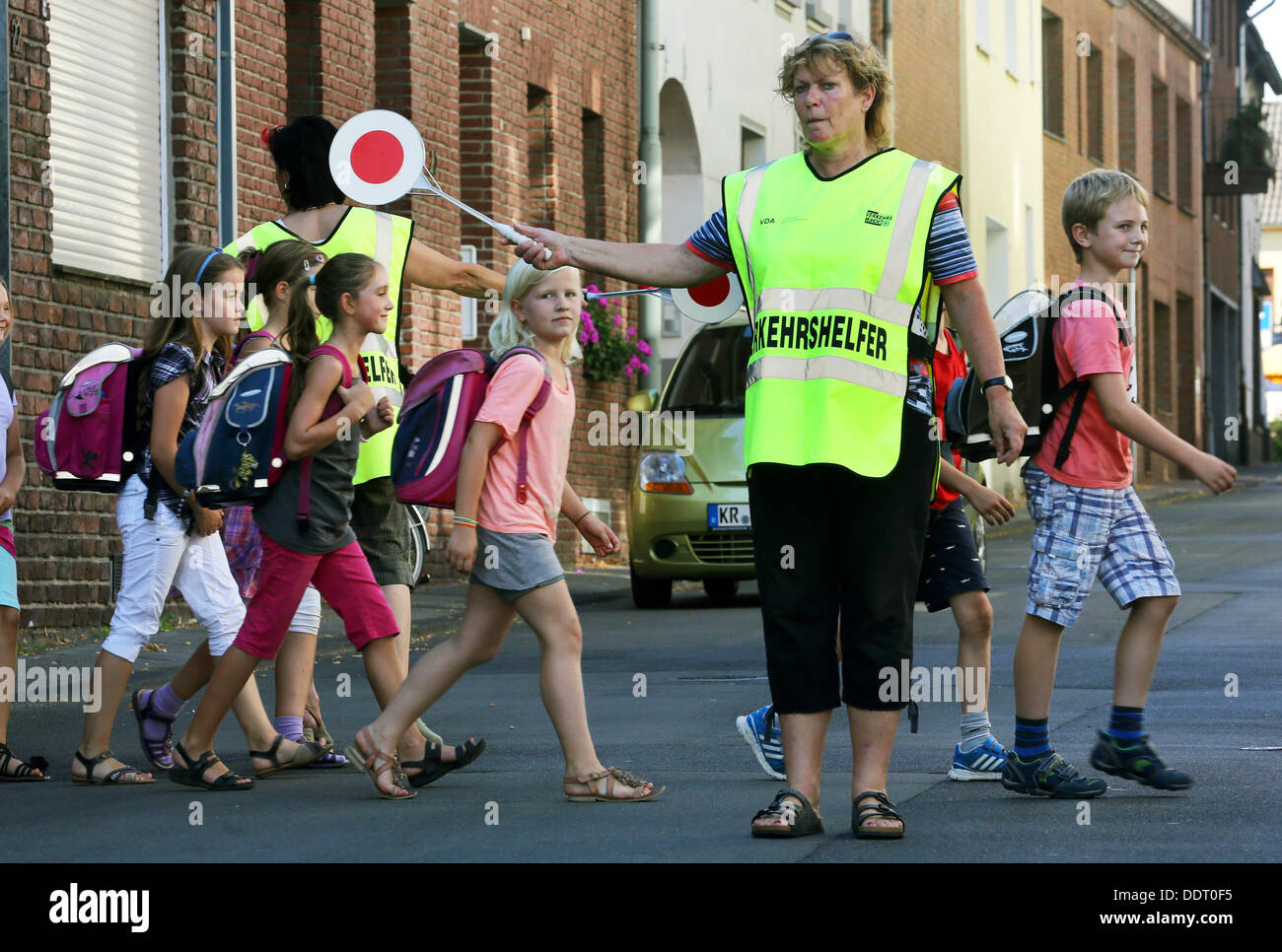 A crossing guard helps elementary school children cross the street in ...