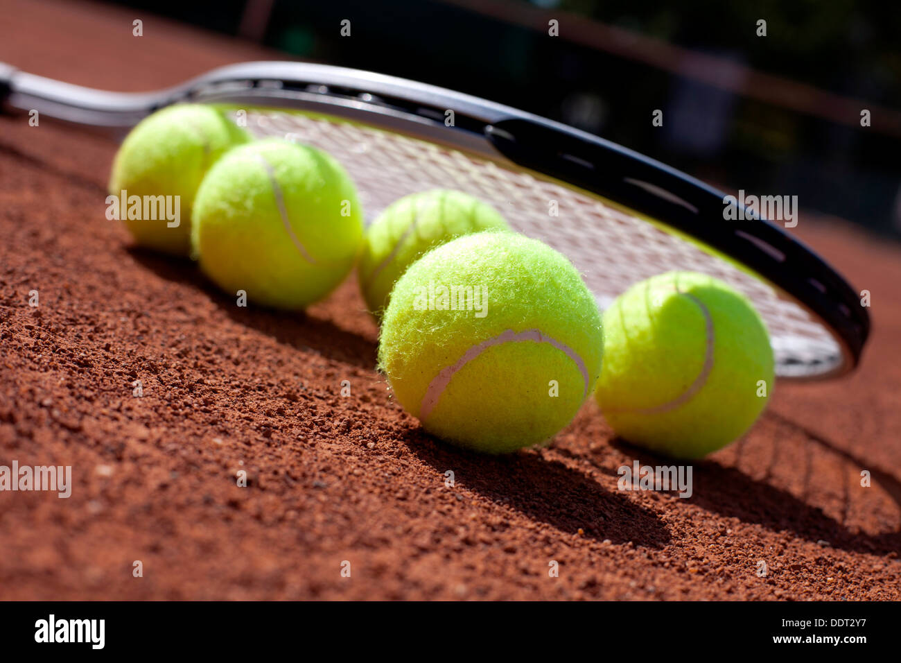 Tennis balls and rocket on court field in sunny day Stock Photo - Alamy