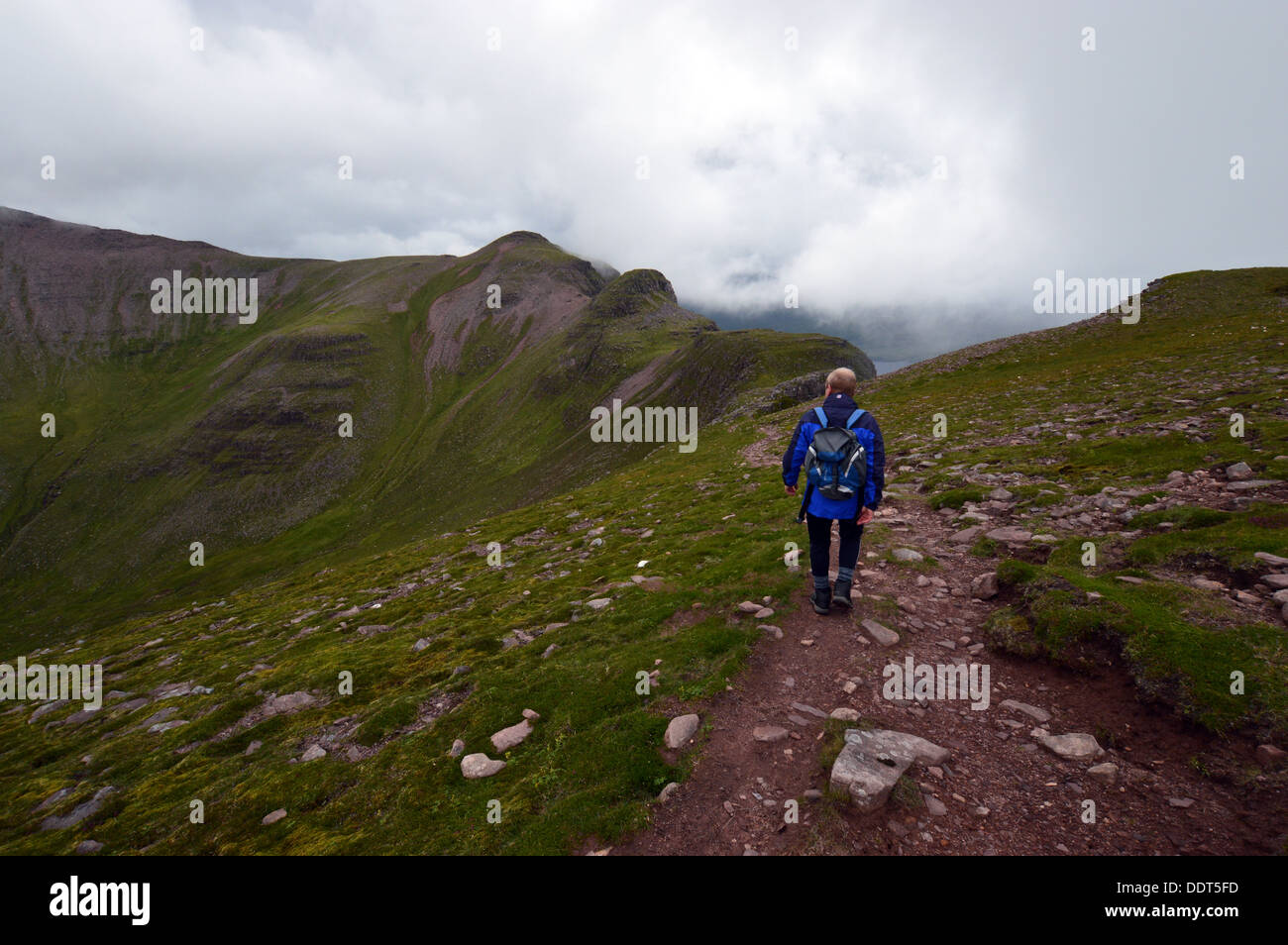 Lone male walker on footpath walking south on the the northern ridge of ...