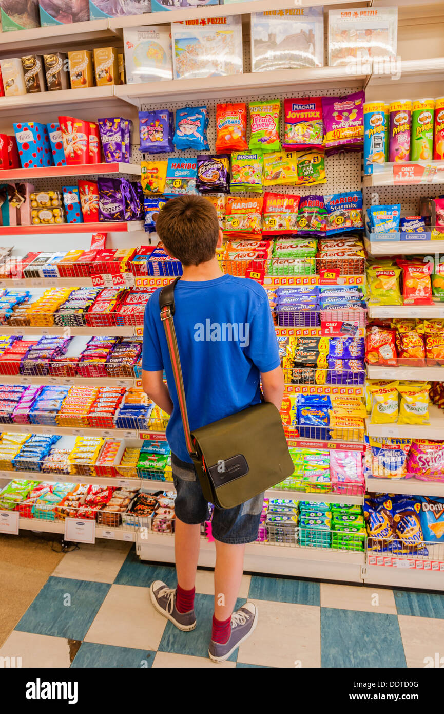 A 13 year old boy choosing some sweets in a shop store in the Uk Stock ...