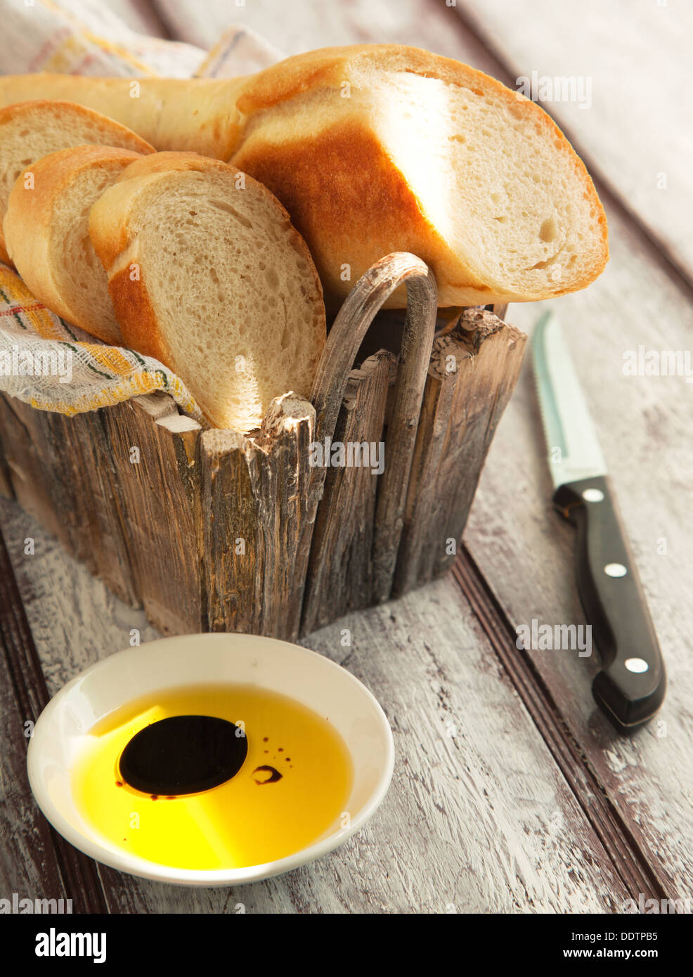 French bread baguette cut on wooden bread board and olive oil ...