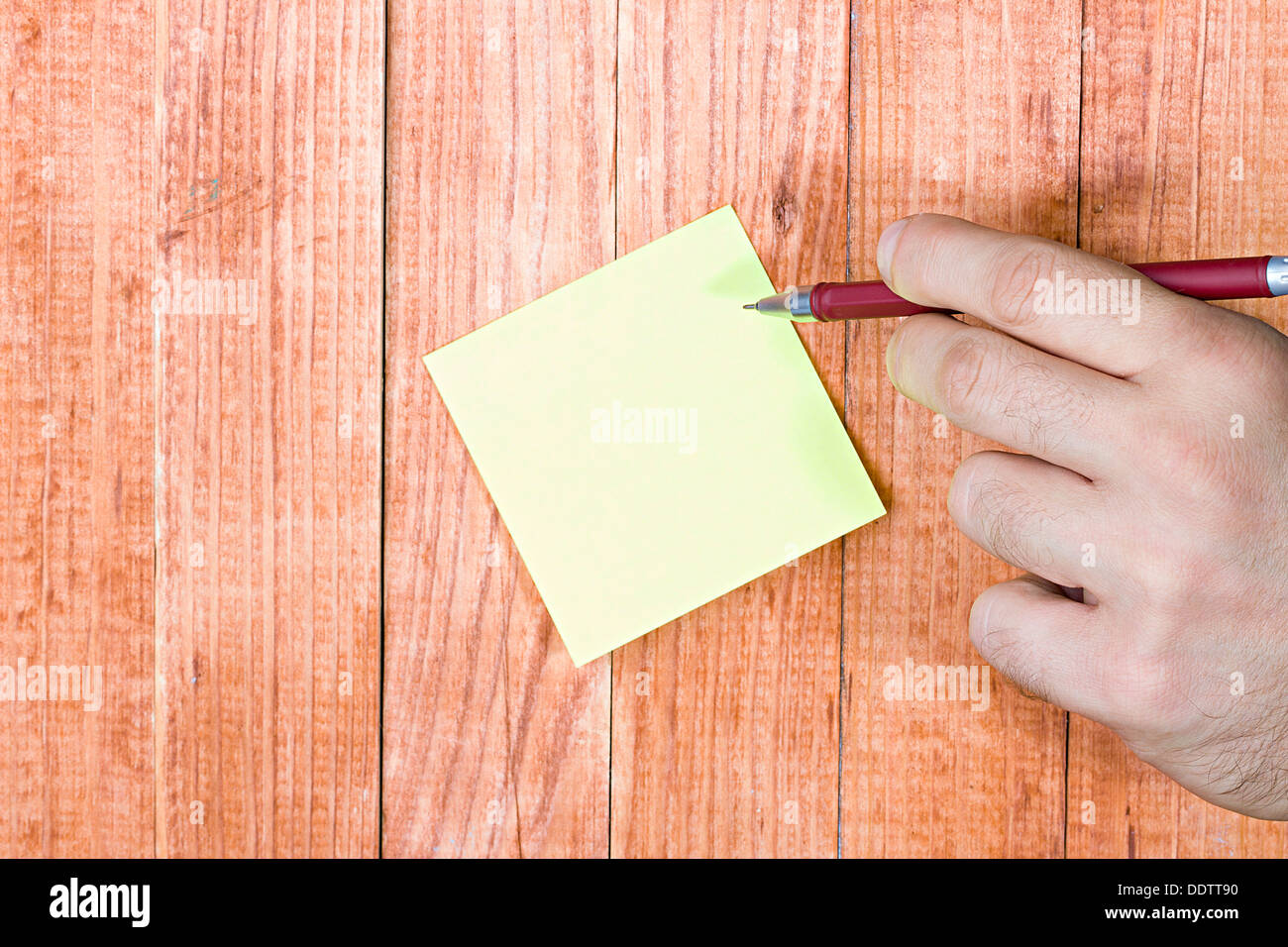 Blank note, paper stick, man's hand holding a pen, on wood background ...