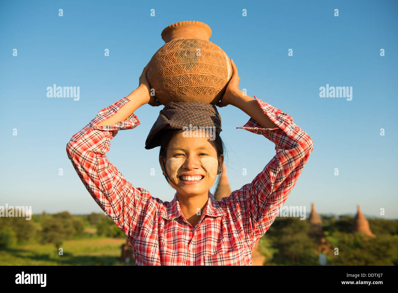 Portrait of Asian traditional female farmer carrying clay pot on head ...