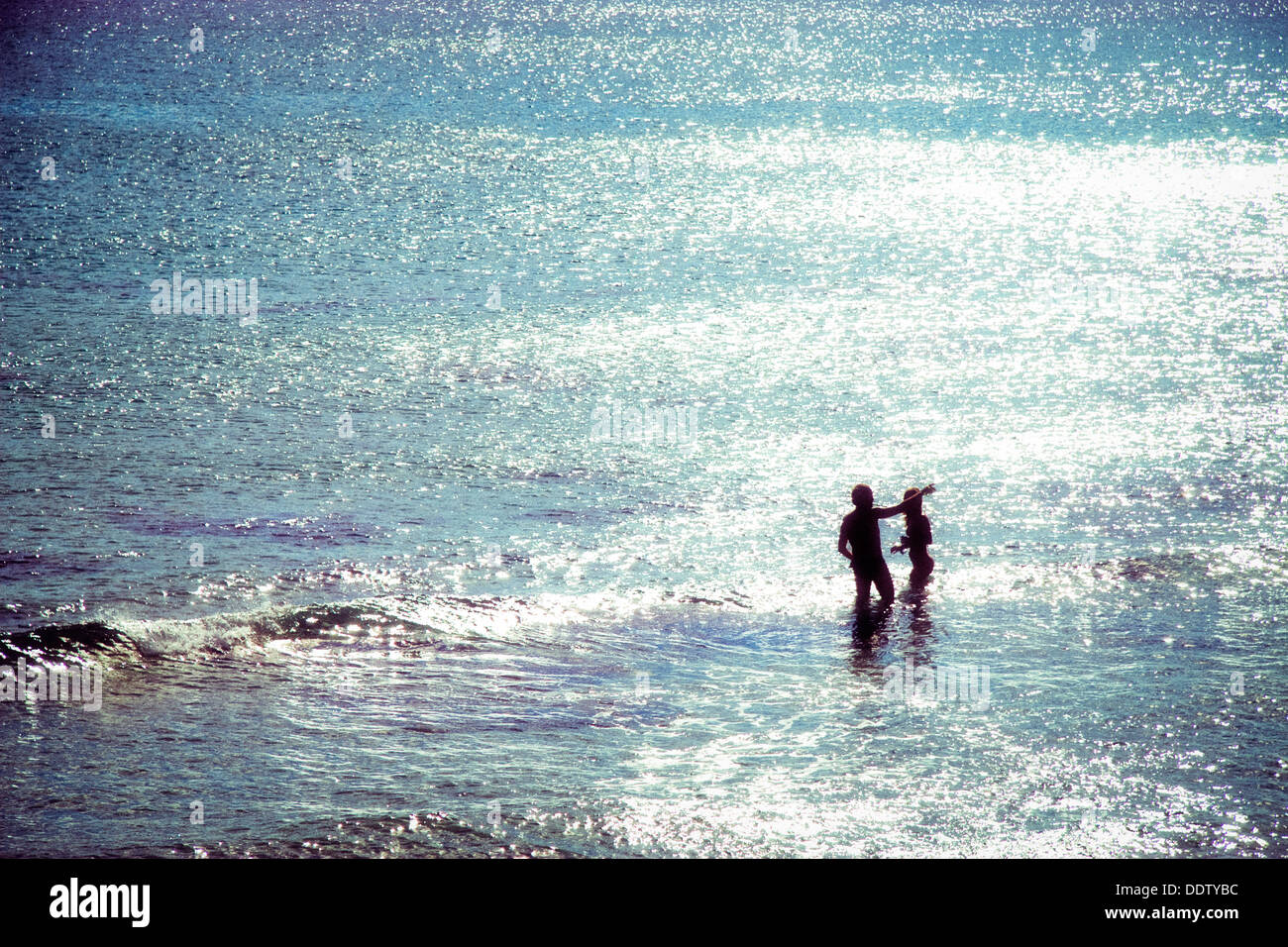 A couple against sunlight taking a bath in sunny Menorca in august, in ...