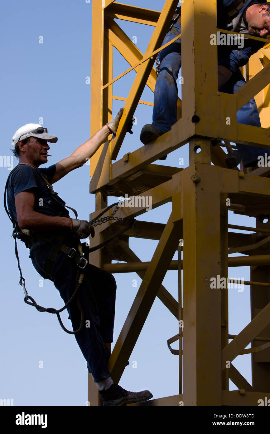 men assembling crane tower segments, new piece being positioned Stock ...