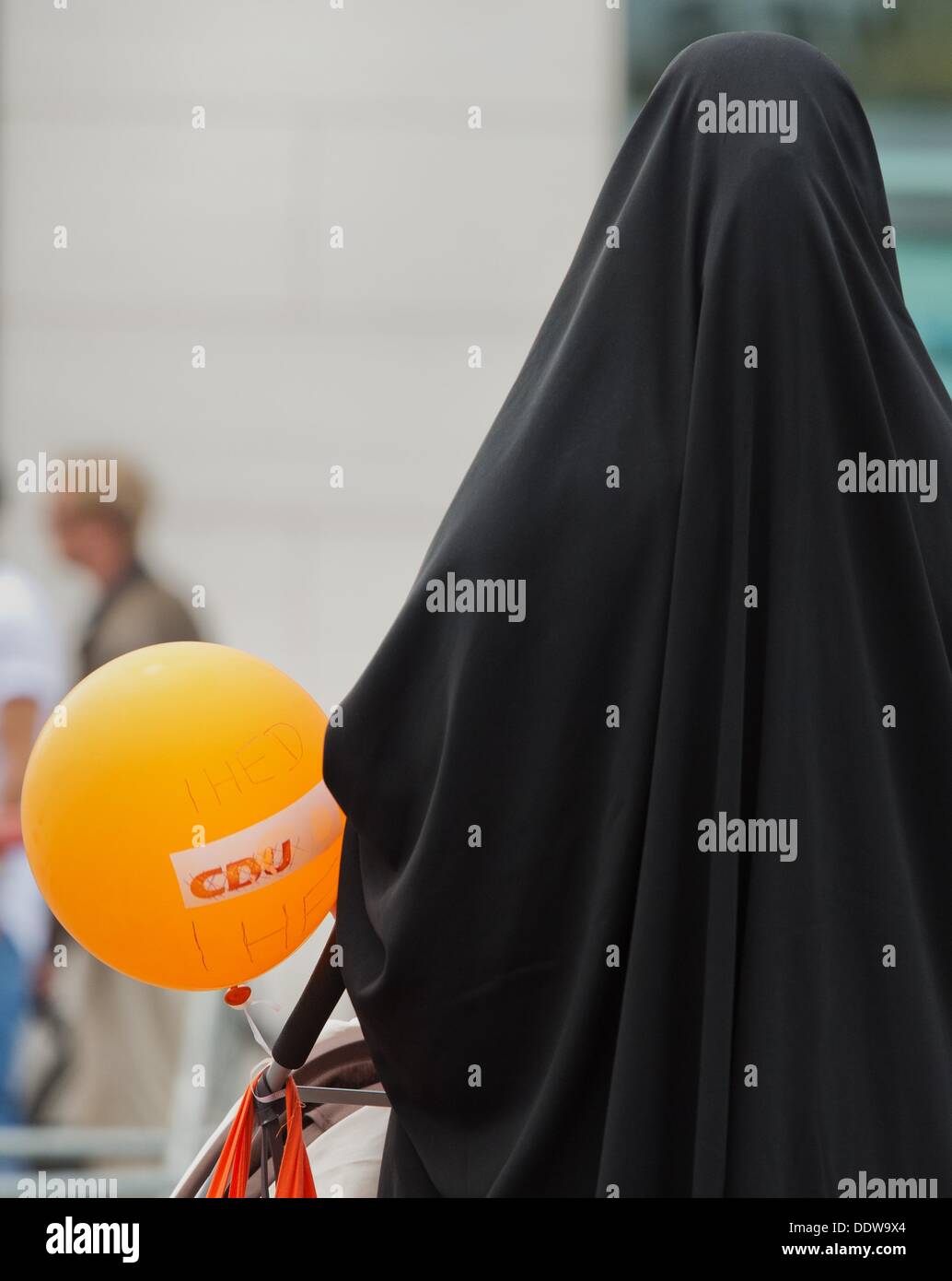 A woman completely covered by a veil with a CDU balloon attends an ...